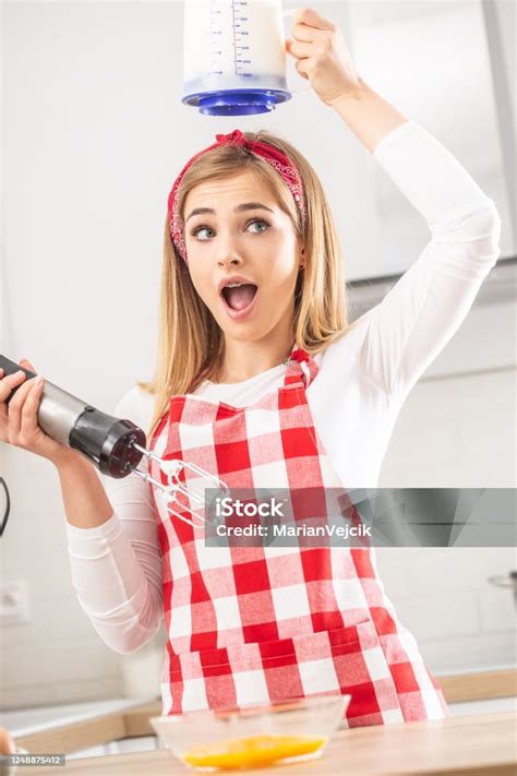 놀란 얼굴 표정을 가진 예쁜 소녀는 한 손에 손을 휘저어 주며 머리 위로 거꾸로 휘저어 달걀 흰자를 들고 있다 가정 주방에 대한 스톡 사진 및 기타 이미지 Istock