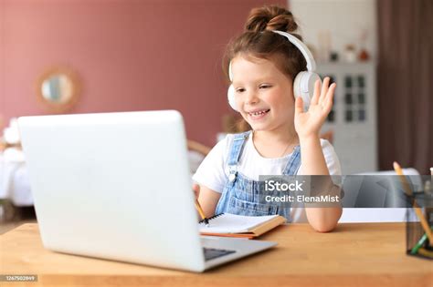 거리 학습 온라인 E러닝 시스템을 통해 공부하는 노트북을 사용하여 헤드폰을 착용하는 쾌활한 어린 소녀 소녀 아이에 대한 스톡 사진 및 기타 이미지 Istock