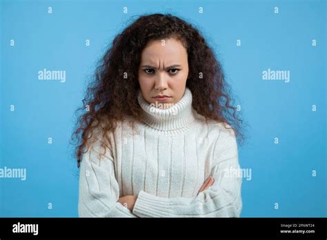 Angry Offended Woman With Curly Hair Keeping Arms Crossed And Staring At Camera With Sceptical
