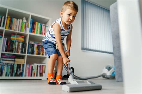 집에서 진공 청소기를 사용하여 작은 아이 아파트에서 작은 소년 청소 바닥 아이가 재미가 있는 가사를하고 여름날에 전면 보기 전체 길이 어린 시절 개발 실제 사람들 개념