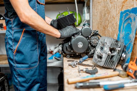 작업장의 작업 테이블에서 수리하는 동안 오토바이 엔진을 분해하는 작업자 얼굴 없이 클로즈업 사진 Unsplash의 우크라이나 이미지
