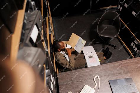 Free Photo African American Cop Drinking Coffee And Analyzing Police Records On Floor Law