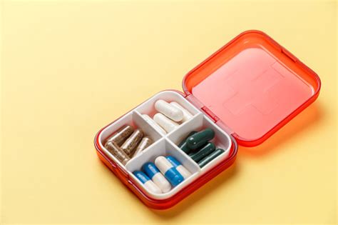 노란색 배경에 의료 알 약과 클로즈업 복용량 알 약 상자 맨 위 보기 플랫 레이 공간을 복사합니다 제약 의약품 알 약 정제 및 캡슐 의학 개념 트렌디한 파스텔 칼라 0명에