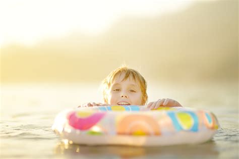 화창한 여름날 바다에서 화려한 떠다니는 반지와 함께 수영하는 어린 소년 깨끗한 물에서 노는 귀여운 아이 가족과 아이들은 여름 방학 동안 휴가를 보냅니다 8 9 살에 대한