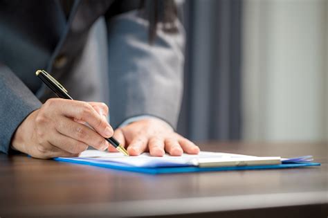 직장 근접 촬영 사람 전문 사업가가 책상에 앉아 펜 서명 또는 서명 계약서를 소지합니다 직장 사무실에서 서류 양식 법인에 계약서를 작성하는 직원 여성 경영자에 대한 스톡