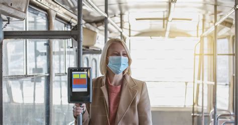 버스 수송에서 보호 얼굴 마스크를 가진 여자 보호용 안면 마스크를 쓴 젊은 여성 그녀는 도시의 버스 수송에 서 있습니다 버스에서 마스크를 쓴 여자 사진