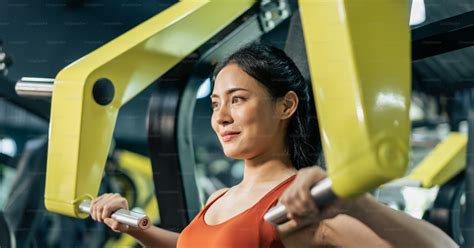 아시아 스포츠맨은 경기장에서 웨이트 머신이나 바벨을 천천히 들어 올립니다 매력적인 젊은 운동 선수 여성 운동 운동은 건강 관리를 위해 웨이트 장비 도구를 사용하고 피트니스