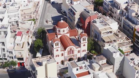 Aerial View Of Agios Nikolaos Crete Showcasing A Red Domed Church White And Beige Buildings