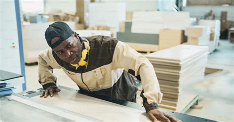 공장에서 기계에 나무 판자를 톱질하는 과정을 통제하는 제복을 입은 진지한 아프리카 남자 사진 Unsplash의 공장 이미지