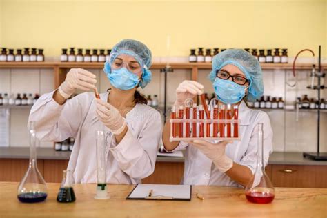 Two Women In Chemistry Laboratory Examining Test Tubes With Red Substance Stock Image Image Of