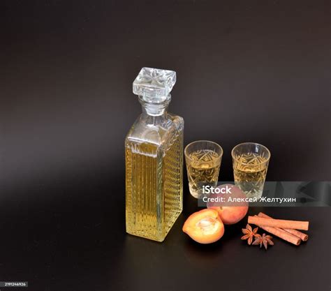 계피와 아니스를 곁들인 복숭아 리큐어 크리스탈 디캔터에 담긴 수제 알코올 검은색 배경에 두 잔 리큐르에 대한 스톡 사진 및 기타 이미지 Istock