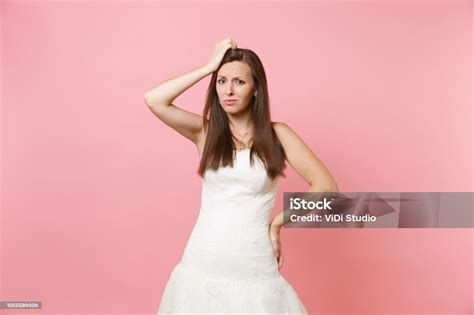 하얀 웨딩 드레스 스탠드에 우려 의아해 신부 여자의 초상화 문제 유지를 핑크 파스텔 배경에 고립 된 머리에 손이 있다 결혼식 축 하 개념입니다 광고에 대 한 공간을 복사