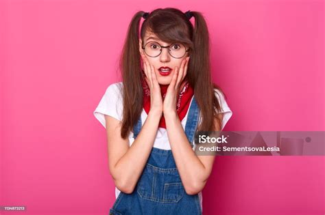 놀란 십 대의 초상화 소녀는 놀라움과 턱이 떨어지고 뺨에 손을 유지 중요 한 작업에 대해 잊고 데님 바지와 여 학생 캐주얼 T 셔츠를 착용 하 고 여 학생은 목에 빨간 큰