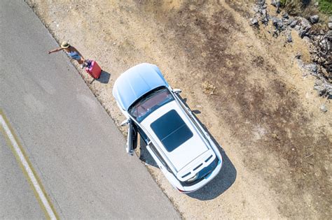 여행 가방 히치 하이킹을 한 여성이 시골 길에서 열린 후드가있는 고장난 차에 서 있습니다 공중 상단 드론 보기 차에 대한 스톡 사진 및 기타 이미지 Istock