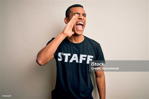 젊은 잘 생긴 아프리카 계 미국인 노동자 남자 흰색 배경 에 직원 유니폼을 입고 외치고 큰 소리로 옆으로 입에 손을 통신 개념입니다 T 셔츠에 대한 스톡 사진 및 기타