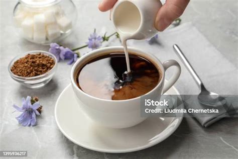 밝은 회색 대리석 테이블에서 맛있는 치커리 음료와 함께 컵에 우유를 붓는 여자 클로즈업 건강한 생활방식에 대한 스톡 사진 및
