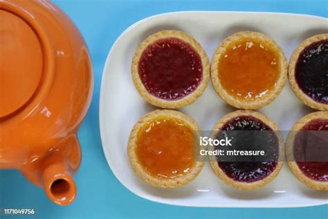 딸기 라즈베리 살구 잼으로 채워진 쇼트 크러스트 페이스트리가있는 작은 수제 잼 타르트 파이의 이미지 애프터눈 티 어린이 생일 파티 음식 뷔페 플래터와 함께 사각 흰색 접시에
