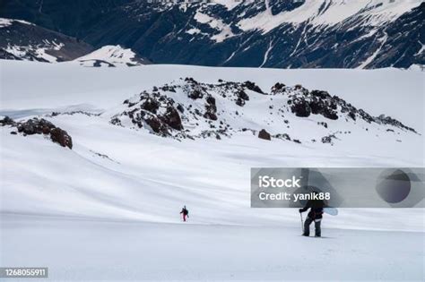 두 명의 여성 스노우보더가 눈의 오지를 통해 산을 오르고 어깨 뒤쪽에 스노우보드를 타고 올라갑니다 프리라이드를 위해 산을 등반 20 24세에 대한 스톡 사진 및 기타 이미지