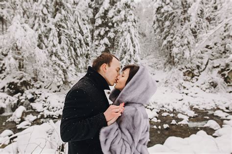 눈 덮인 겨울 산에서 수용 하는 세련 된 커플 행복 한 로맨틱 남자 고 명품 옷 눈에 폭포에 부드럽게 키스 여자 휴일도 함께입니다 텍스트를 위한 공간 2명에 대한 스톡 사진