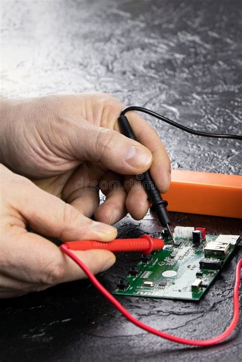 An Electrician Takes Readings From A Microcircuit Using A Multimeter Measuring Instruments