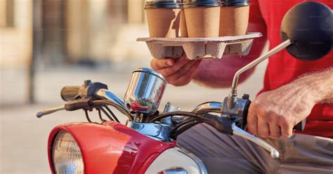스쿠터에 4 개의 커피 컵을 배달하는 남성 택배 햇볕이 잘 드는 거리에 서 음식 배달 개념 사진 Unsplash의 특급 배송 이미지