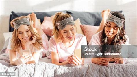 파자마 파티 동안 침대에 누워 스마트 폰을 사용 하 여 잠자는 마스크에 아름 다운 웃는 다민족 소녀 3 명에 대한 스톡 사진 및 기타 이미지 Istock