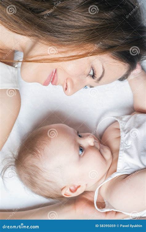 Счастливая мать при младенец лежа на белой кровати Стоковое Изображение изображение