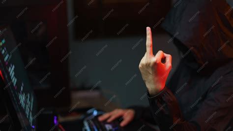 Premium Photo Hacker In Hoodie Showing Middle Finger And Typing Code