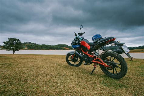 Free Images Bike Dark Clouds Daylight Grass Helmet Lake