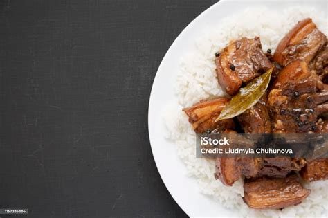 수제 필리핀 아도보 돼지고기에 쌀을 얹은 검은 표면 위에 흰 접시를 얹어 꼭대기를 바라볼 수 있습니다 평면 누워 오버 헤드 위에서 공간을 복사합니다 0명에 대한 스톡 사진