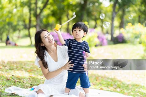 행복한 아시아 가족은 휴일에 야외에서 함께 시간을 보내고 있습니다 공원에서 비누 거품을 가지고 놀고있는 아시아 어머니와 어린 소년 웃는 유아 어린 소년 재미 비누 거품을