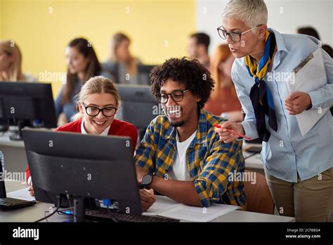 Teacher In Classrom Looking Pupils Task On Theirs Computer Stock Photo Alamy