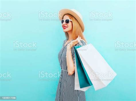 여름 밀짚 라운드 모자를 쓰고 쇼핑백을 들고 행복한 미소 짓는 여성 파란색 배경에 검은 색 흰색 줄무늬 드레스 세일에 대한 스톡 사진 및 기타 이미지 Istock
