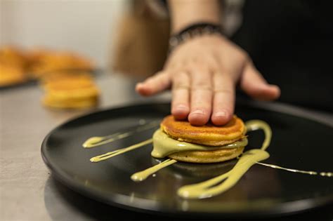 한 여성이 피스타치오 소스가 들어간 미국 팬케이크를 아침 식사를 위해 접시에 올려 놓습니다 30 34세에 대한 스톡 사진 및 기타 이미지 Istock