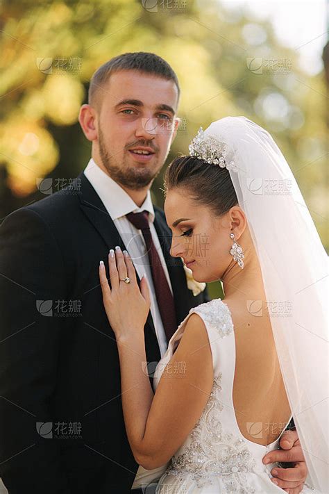 美丽的新娘和她的丈夫在公园里。黄树的背景。幸福的夫妇