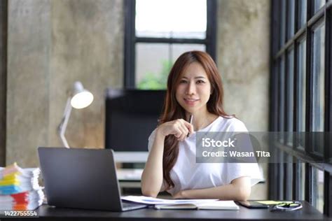 캐주얼하게 옷을 입은 아시아 여성이 홈 오피스에서 노트북과 문서를 작업하고 있습니다 재택 근무 개념 학생에 대한 스톡 사진 및