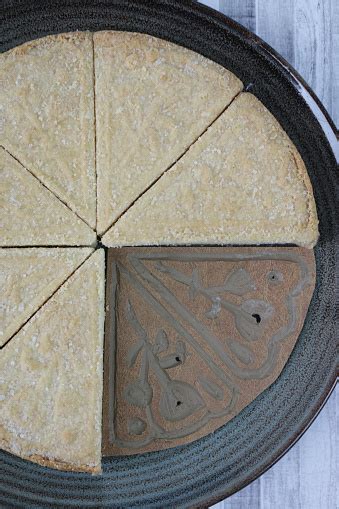 엉겅퀴 금형 패턴 세부 사항을 보여주는 슬라이스 버터 수제 쇼트 브레드 라운드의 이미지 오븐에서 신선한 황금 갈색 회색 접시와 엉겅퀴 디자인 금형에 삼각형으로 잘라 흰색