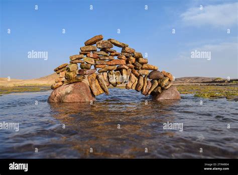 A Picturesque Stone Bridge Arches Over A Tranquil Blue Body Of Water With The White Crested