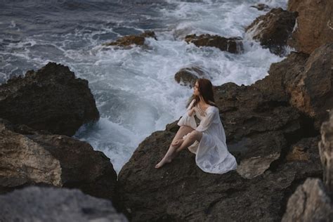 Premium Photo Pretty Woman With Wet Hair In White Dress Sits On Waves Stones