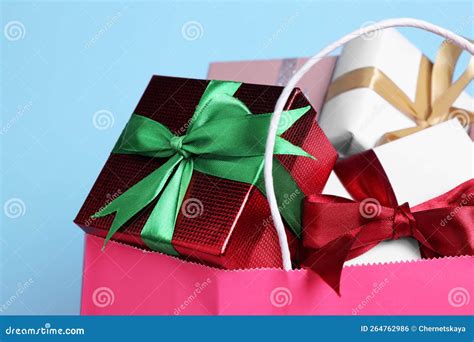 Saco De Compras De Papel Cor De Rosa Cheio De Caixas Presentes Em Pano De Fundo Azul Claro Foto