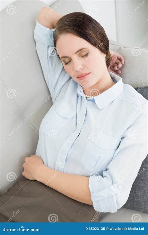 Женщина одетая колодцем красивая отдыхая на софе Стоковое Изображение изображение