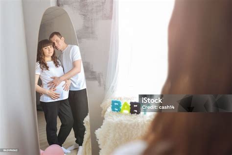 행복 한 젊은 커플 기대 아기 서 함께 포용 하 고 거울 보고 남자가 그의 임신한 아내의 배를 들고 있다입니다 거울에 대한 스톡 사진 및 기타 이미지 Istock