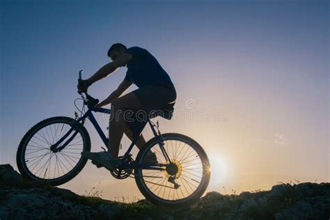 Silhouette De Un Motociclista Macho Cabalgando Su Bicicleta Cuesta Arriba En Un Terreno Rocoso Y