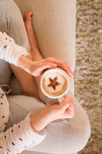 실내에 소파에 앉아 커피잔과 소녀 집에서 커피 또는 차 앉아 아늑한의 잔을 마시는 여자 휴식과 휴식 계 피 스타와 카푸치노입니다