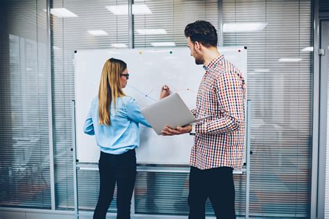 전문 여성 교사 대학에서 개인 수업 중 손에 현대 넷북과 숙련 된 학생에게 교육 자료를 설명하는 흰색 플립 차트에 그래픽 체계를