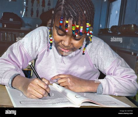 Black Female Middle School Student Works At Desk With Workbook Stock