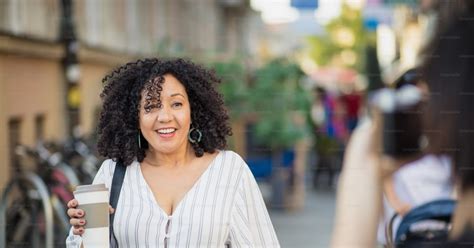 웃는 여자가 커피 한 잔과 함께 거리를 걷고 있다 그녀의 사진을 찍는 여자 사진 Unsplash의 세르비아 이미지