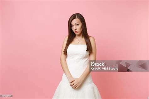 하얀 웨딩 드레스에 불만족된 화가 신부 여자 공격 핑크 파스텔 배경에 고립 된 그녀의 앞에 넘어 손을 잡고 걸릴 결혼식 축 하 개념입니다 광고에 대 한 공간을 복사 합니다