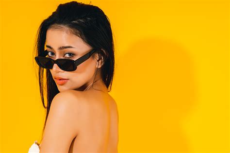 매력적인 아름다운 젊은 아시아 여자는 노란색 배경과 그림자와 함께 여름 시즌에 선글라스를 착용하고 세련된 소녀는 아름다움을