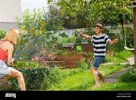 Teen Laughs While Engage In A Water Gun Game With His Mother Stock
